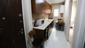 Cozinha compacta com micro-ondas, chaleira e uma pequena mesa de jantar com cadeiras.