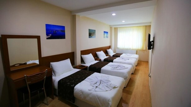 Quarto de hotel com quatro camas, uma escrivaninha e uma cadeira.