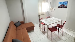 Uma sala de estar moderna com um sofá seccional, uma mesa de jantar com cadeiras e um radiador.