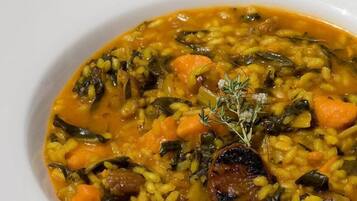 Uma tigela de sopa com legumes e ervas.