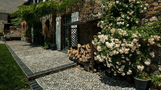 Um edifício de pedra com um caminho de cascalho e flores brancas.