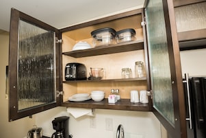 Cozinha com armários abertos, contendo diversos utensílios e eletrodomésticos.