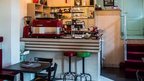 Um restaurante com área de bar, mesas e uma máquina de café.