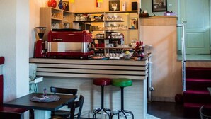 Um restaurante com área de bar, mesas e uma máquina de café.