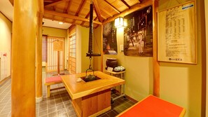 Um quarto japonês tradicional com tatames, uma mesa de madeira baixa, um candeeiro pendente e um cartaz na parede.