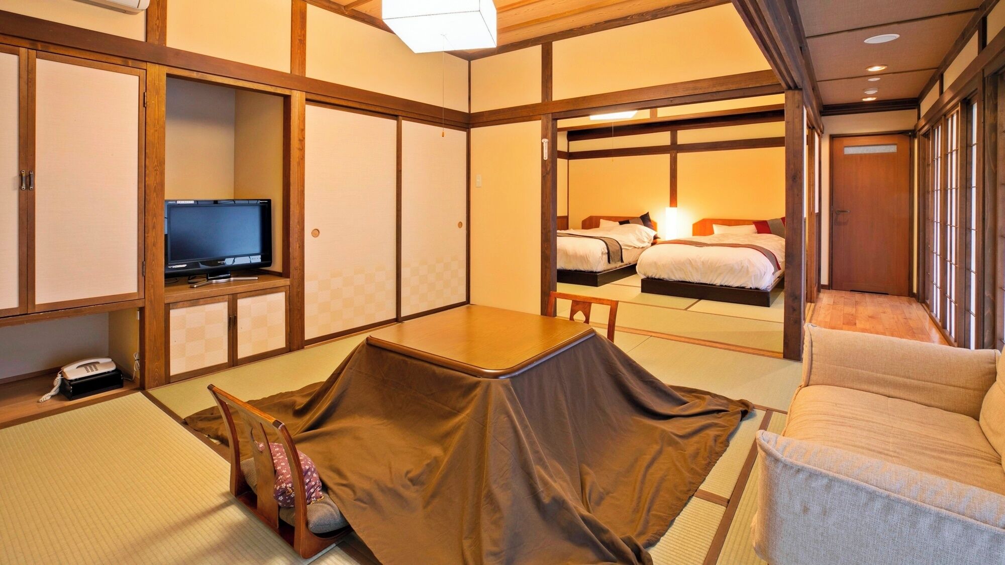 Quarto japonês tradicional com tatames, televisão, escrivaninha e cama com vista para o exterior.