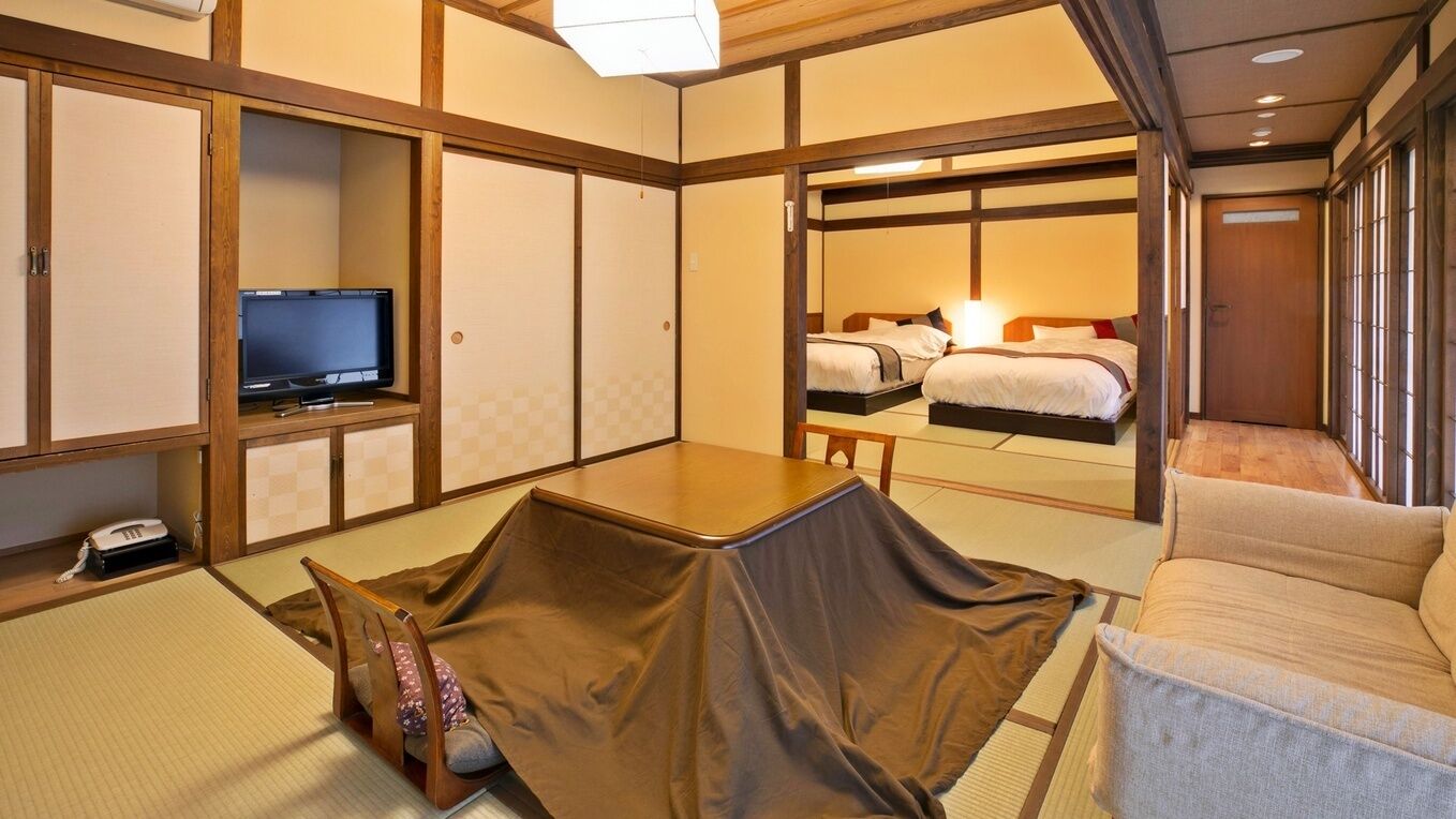 Um quarto tradicional japonês com tatames, televisão, sofá e cama.