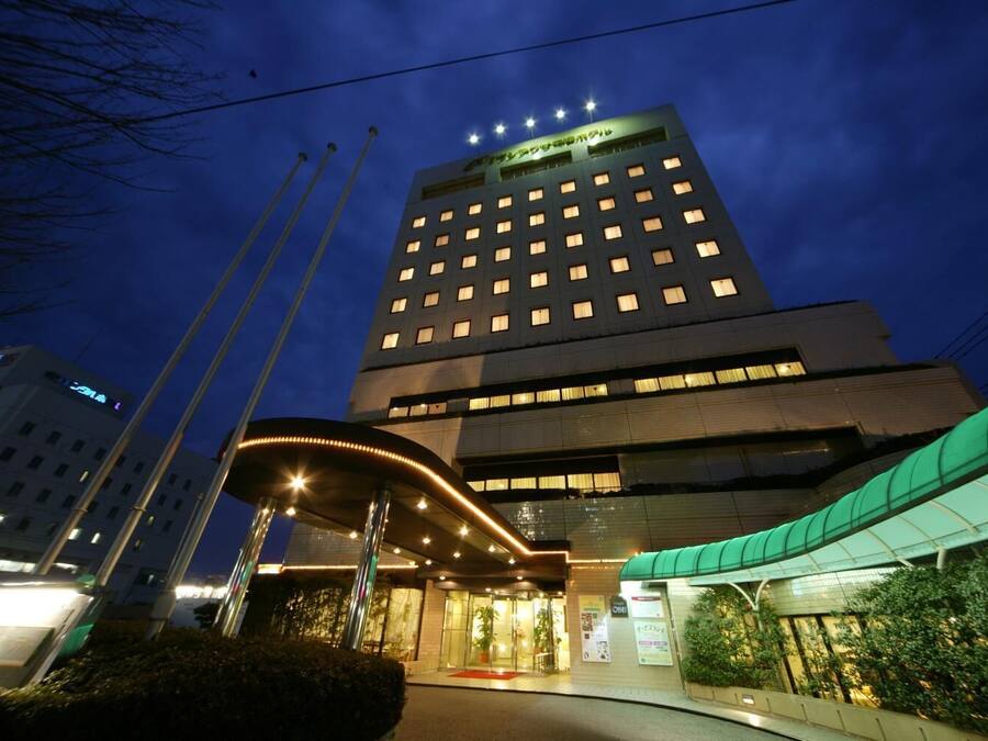 Um hotel de vários andares com design moderno, destacando uma entrada imponente com teto curvo e galeria coberta.