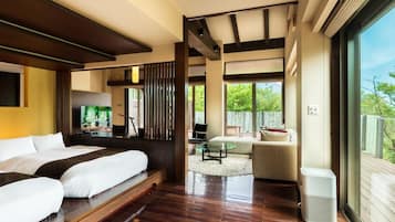 Quarto de hotel moderno com uma cama grande, um espaço de estar e vista para o exterior.