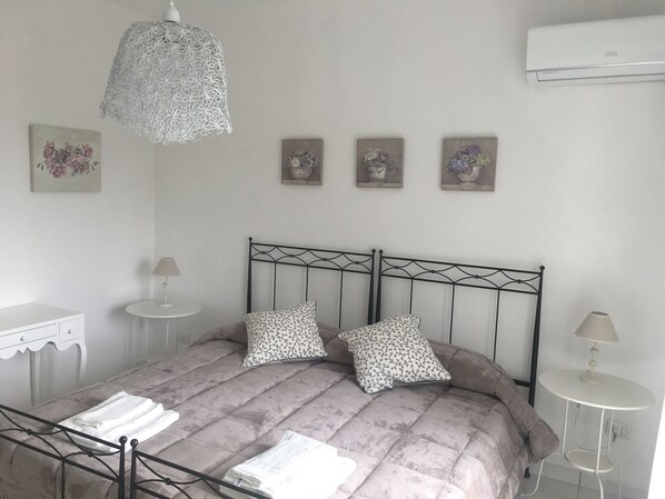 Quarto bem arrumado com cama, mesas de cabeceira e obra de arte na parede.