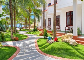 Resort com calçada pavimentada, palmeiras e áreas de estar ao ar livre.