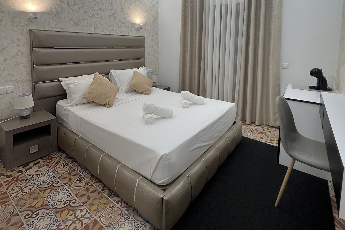 Quarto de hotel moderno com uma cama grande, uma escrivaninha e uma cadeira.