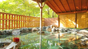 Uma onsen japonesa tradicional com deck de madeira, banheira de pedra e cerca de madeira.