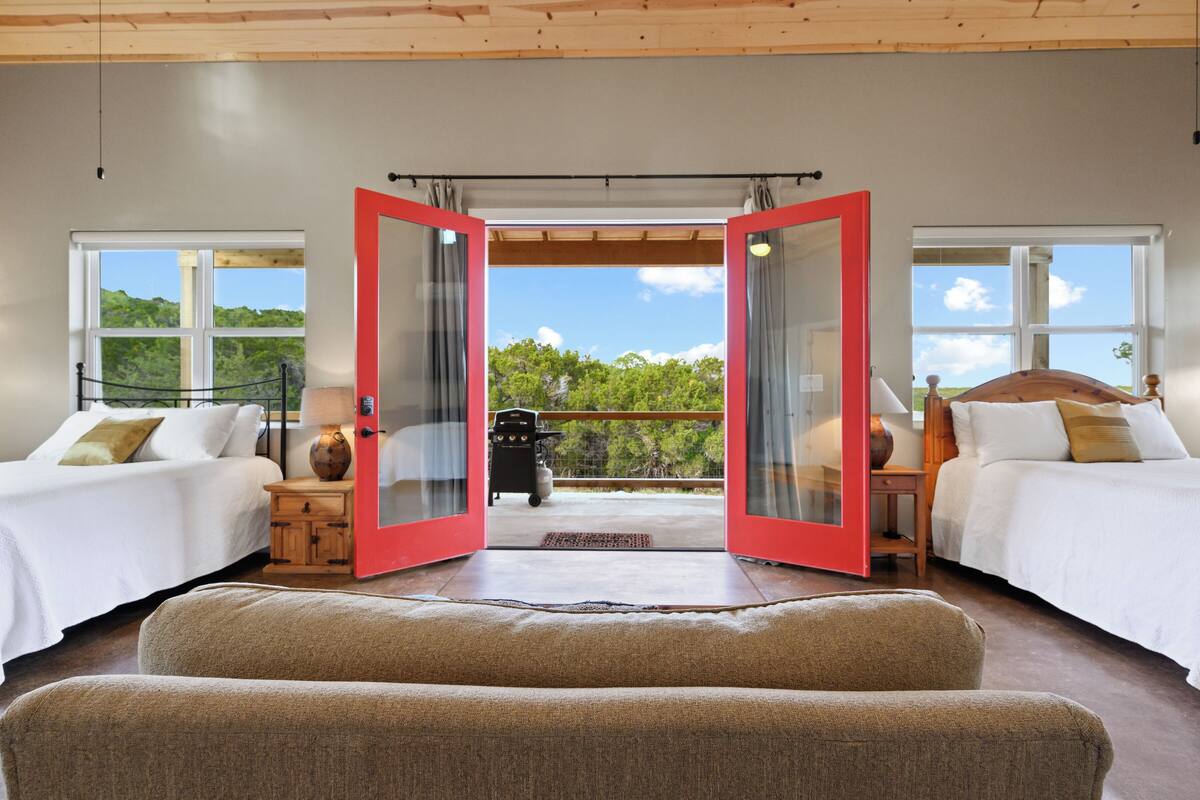 Quarto com duas camas, um banco e vista para o exterior.