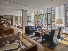 Um lobby moderno de hotel, com amplas janelas, área de estar e uma biblioteca.