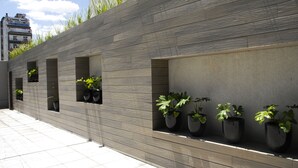 Fachada moderna de edifício com painéis de madeira verticais e janelas retangulares.