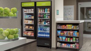 A hotel lobby with two refrigerated beverage dispensers labeled "really cold" and "cold," and a shelf stocked with snacks and beverages.