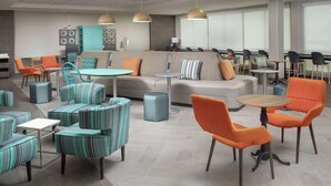 Uma área de estar moderna com disposição de assentos, mesas e elementos decorativos.