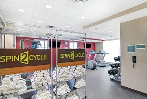 Uma área de ginástica com sinal spin2cycle, equipamentos de exercício e toalhas.