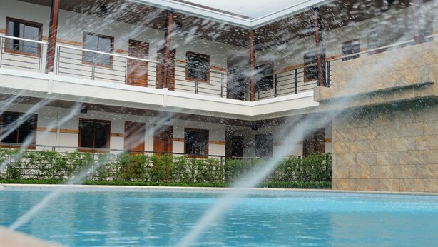 Um hotel moderno com piscina, um elemento aquático e uma estrutura de dois andares com varandas.