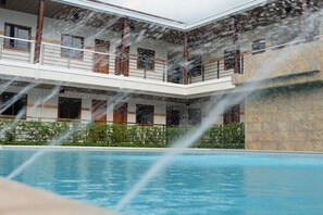 Um hotel moderno com piscina, um elemento aquático e uma estrutura de dois andares com varandas.