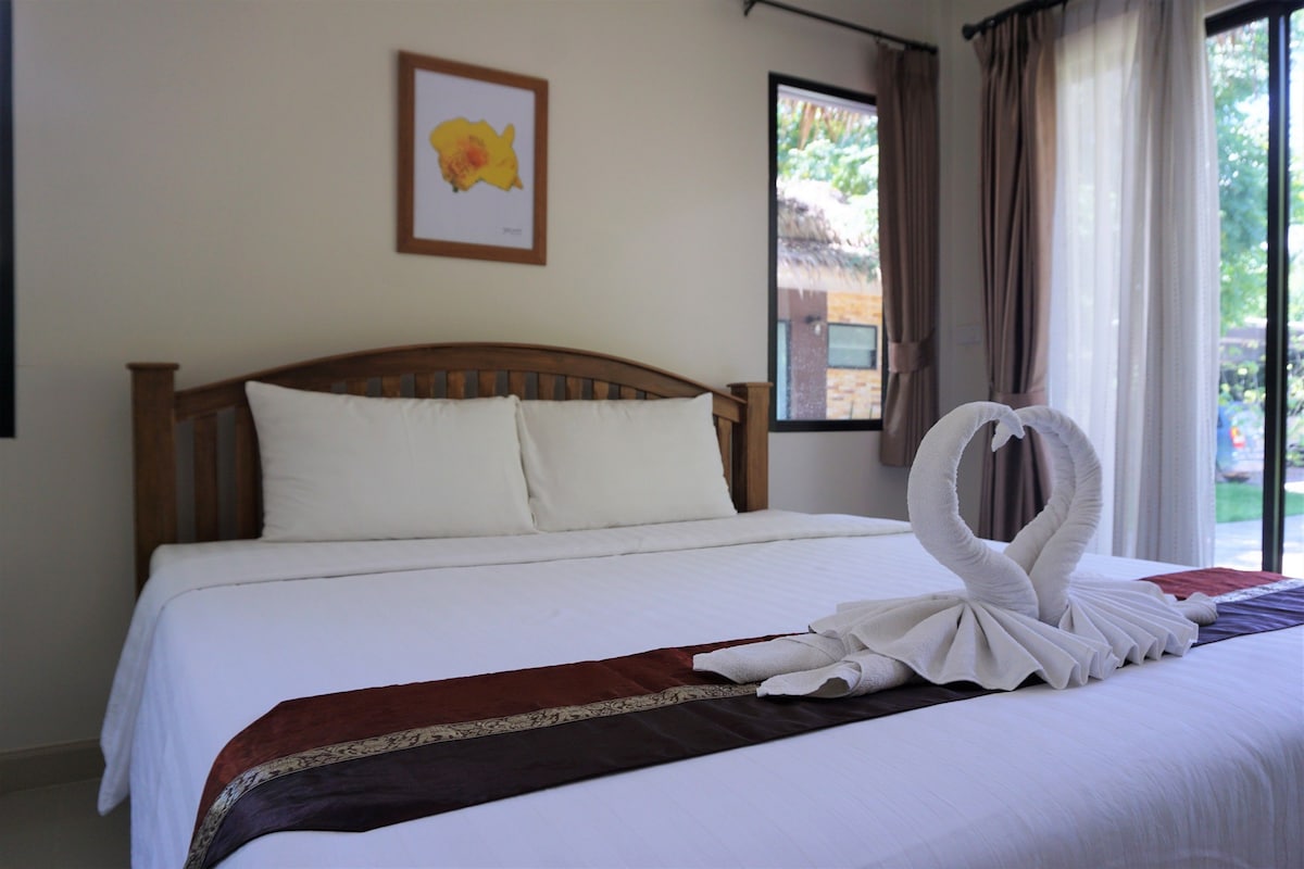 Quarto de hotel com cama, quadro pendurado na parede e janela com cortinas.