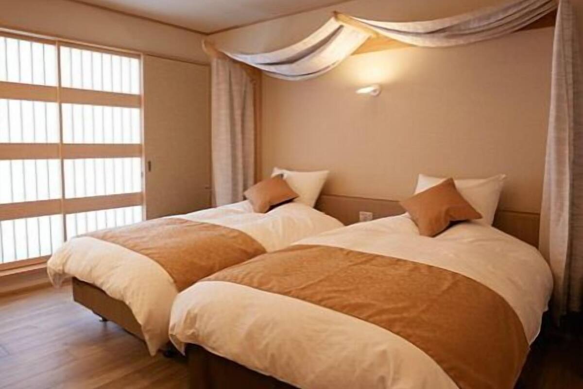 Quarto de hotel com duas camas, uma janela grande e um design moderno no teto.