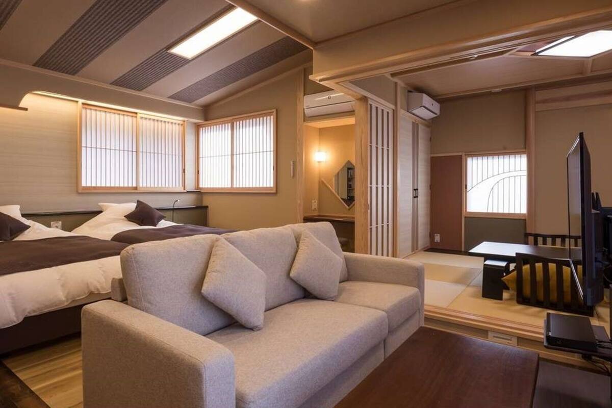 Quarto de hotel com cama, sofá, televisão e escrivaninha.