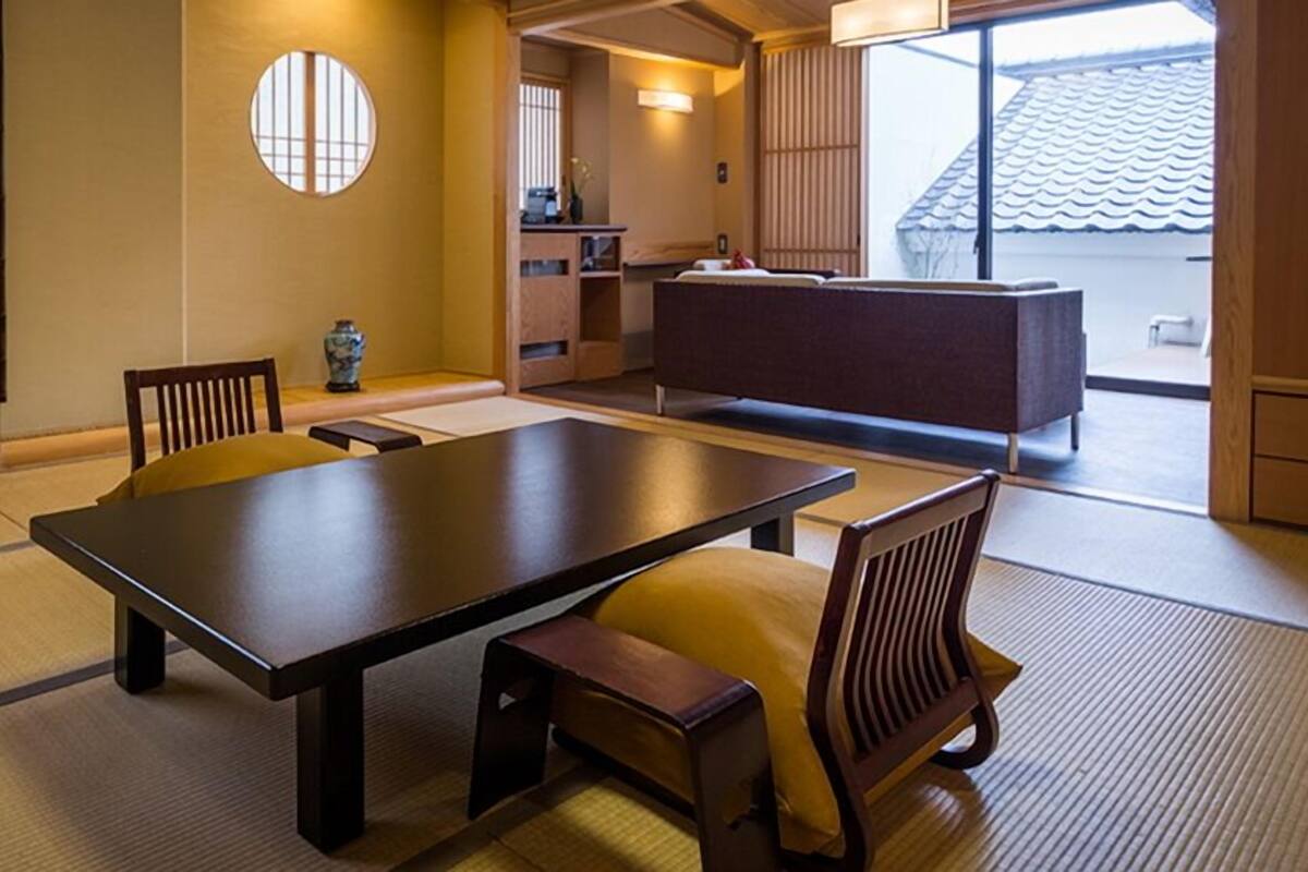 Um quarto japonês tradicional com tatames, uma mesa baixa e mobiliário de madeira.