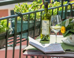 Uma garrafa de vinho, um copo de vinho branco e um caderno sobre uma mesa ao ar livre.