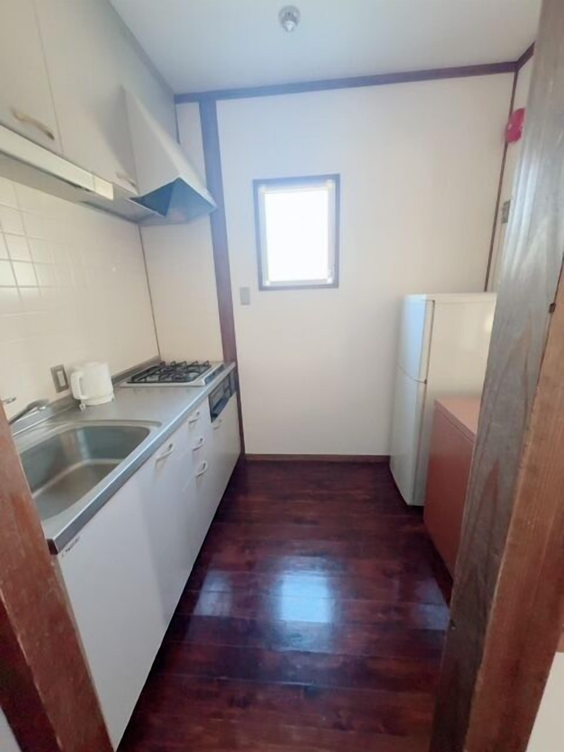 Cozinha compacta com pia, fogão e uma pequena janela.