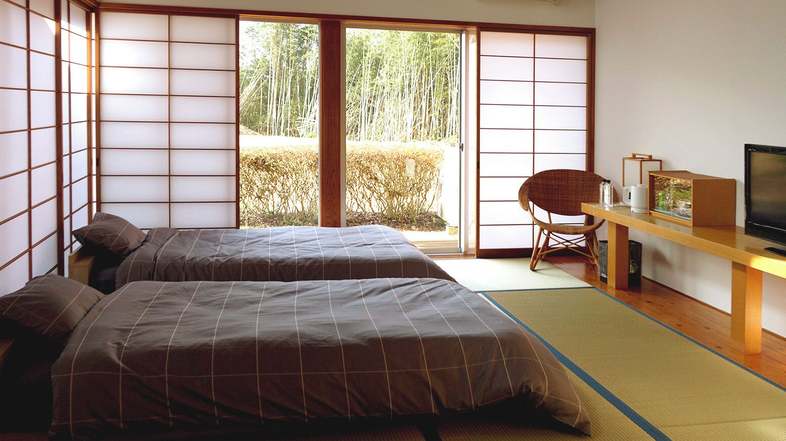 Um quarto em estilo japonês tradicional, com piso de tatame, uma porta deslizante para um jardim e uma cama com futon.
