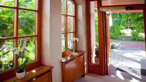 Quarto com grandes janelas, um banco de madeira e um vaso com planta.