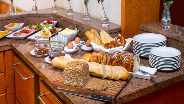 Um buffet de café da manhã com diversos pães, doces e acompanhamentos.