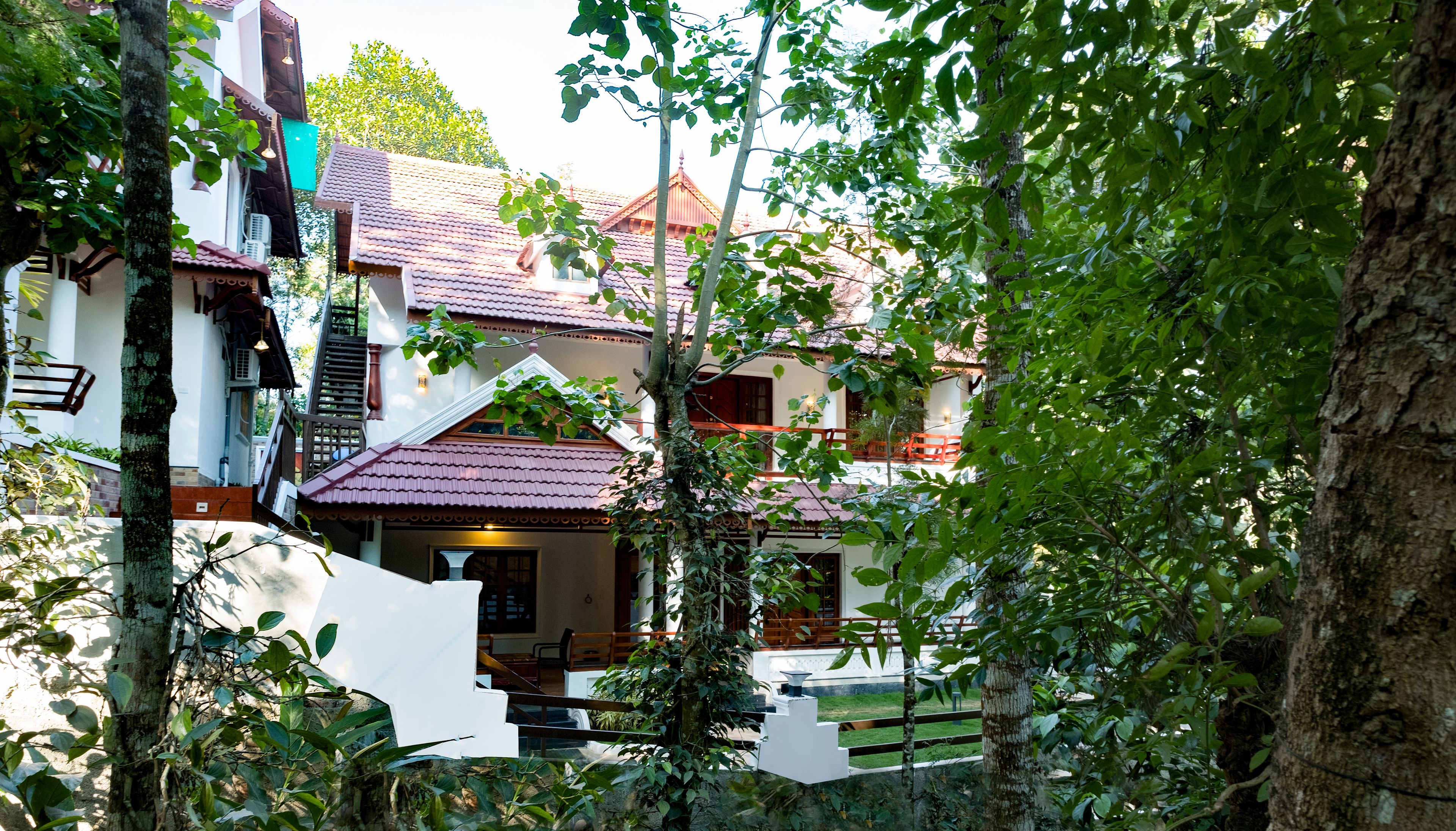 Uma casa tradicional com telhado de cerâmica, cercada por vegetação exuberante e árvores.