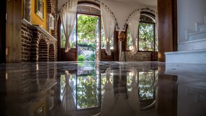 Um quarto espaçoso com soalho polido, paredes de tijolo e grandes janelas com cortinas brancas.
