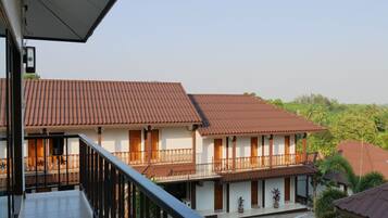 Um edifício de dois andares com telhado em telhas e uma varanda com guarda-corpo.