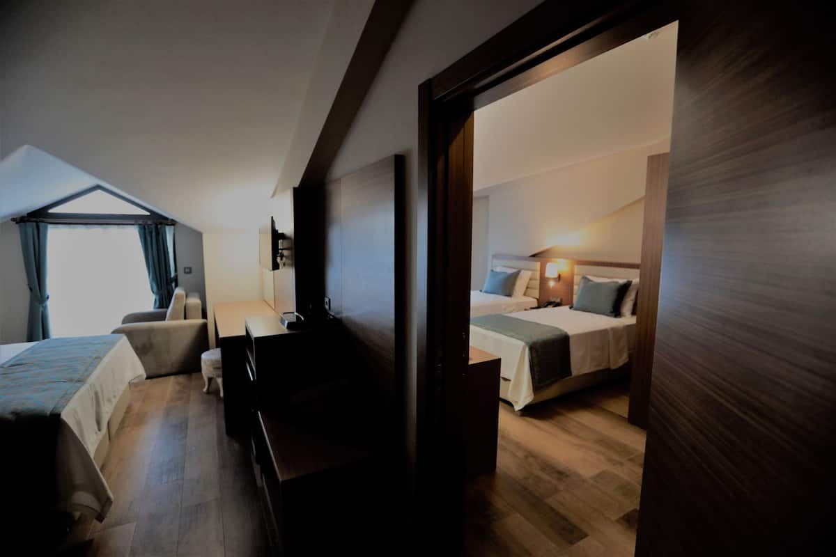 Quarto moderno com cama estilo loft, uma escrivaninha e um pequeno espaço de estar.