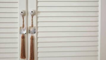 Uma porta branca com ripas horizontais e dois objetos decorativos pendurados nela.