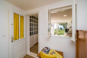 Quarto compacto com uma mesinha, uma cadeira e uma janela com vista para o exterior.