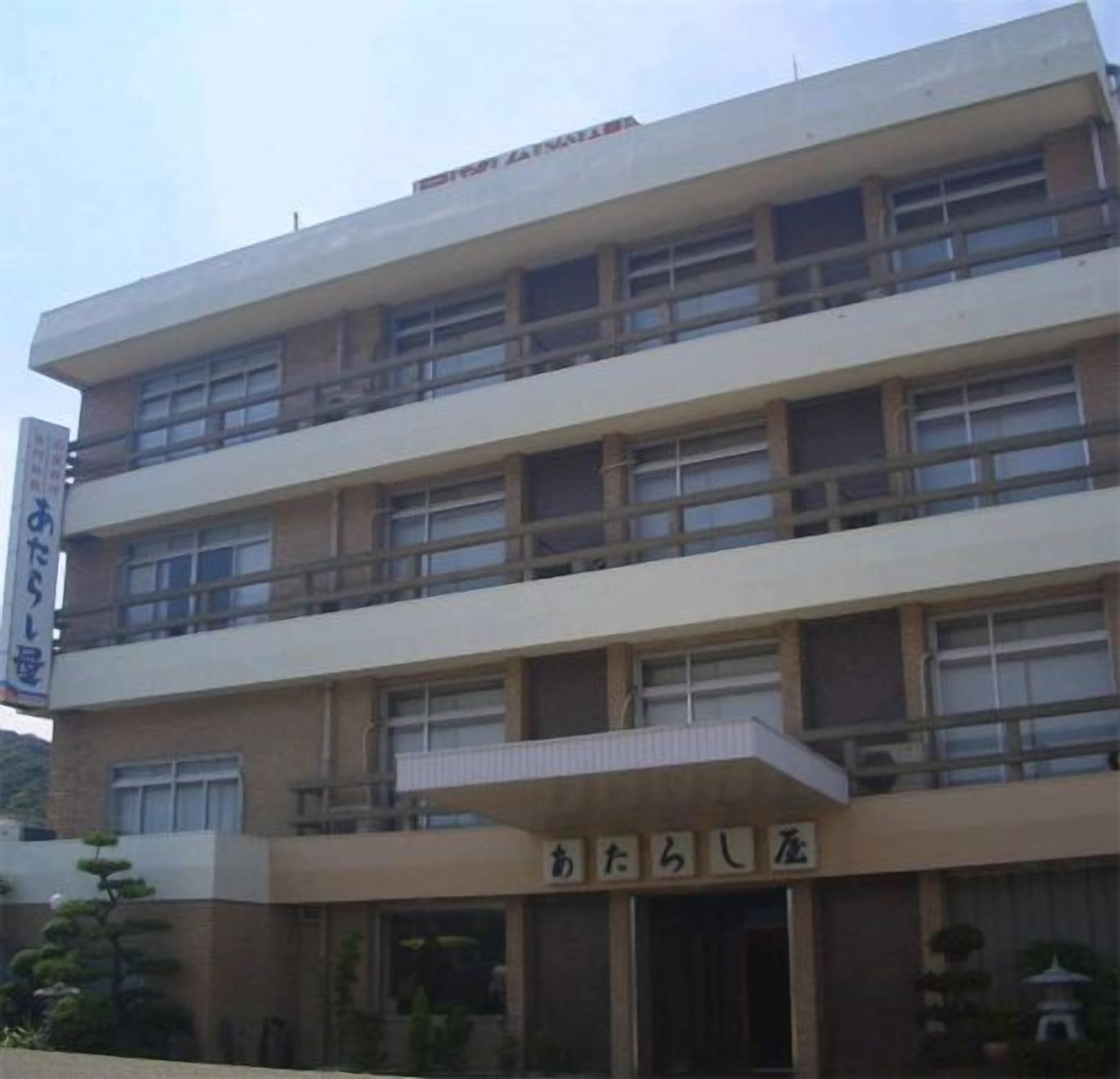 Um edifício de vários andares com fachada plana, janelas amplas e uma placa com caracteres japoneses.