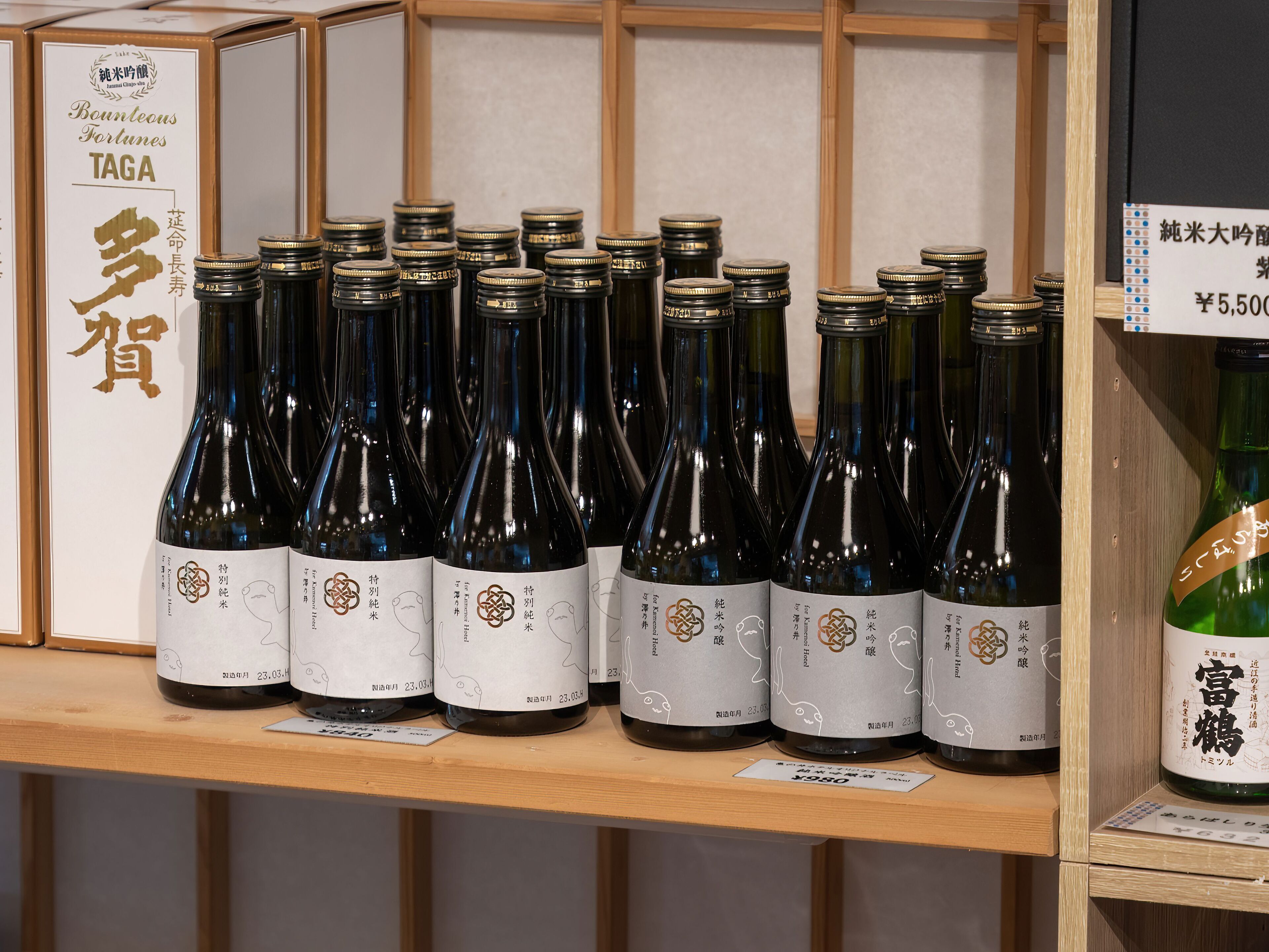 Uma estante com várias garrafas de vinho, cada uma com etiqueta com caracteres japoneses e um preço.