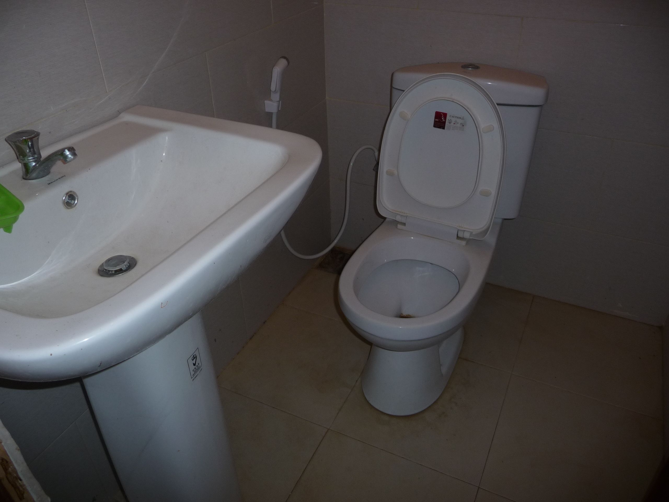 Casa de banho com uma sanita e lavatório brancos.