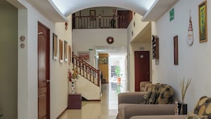 Um hall de hotel com uma escada, um balcão de recepção e dois sofás.