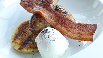 Um prato com panquecas, ovo pochê e bacon.