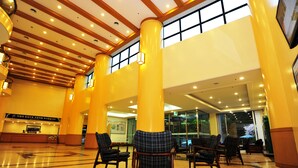Um hall amplo com pé direito alto, grandes janelas e um balcão de recepção.