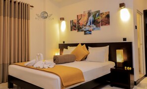 Quarto de hotel com cama bem arrumada, cabeceira e três luminárias fixadas na parede.