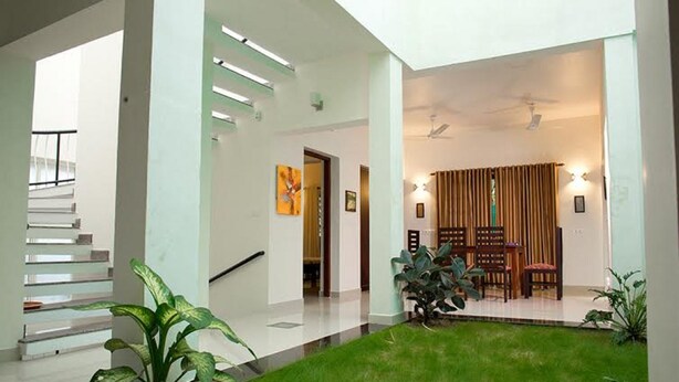 Um interior moderno com escadas, área de refeições e um pequeno jardim.