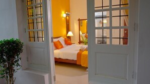 Quarto de hotel com cama, mesa de cabeceira, abajur e espelho.