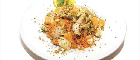 Um prato branco com uma porção de comida, incluindo gomos de laranja e um enfeite verde.